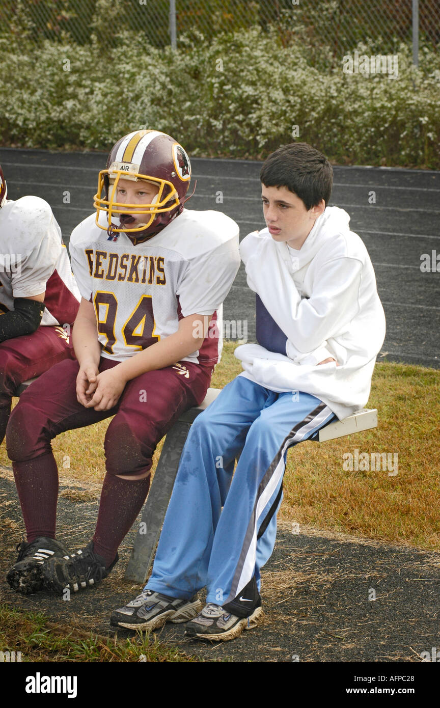 Injured young football player on bench with arm in cast from injury and ...