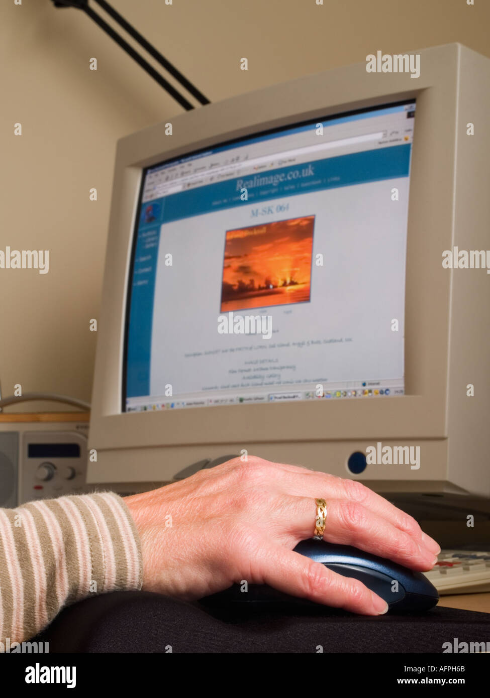 Person working at a computer with hand on mouse and website on an old ...