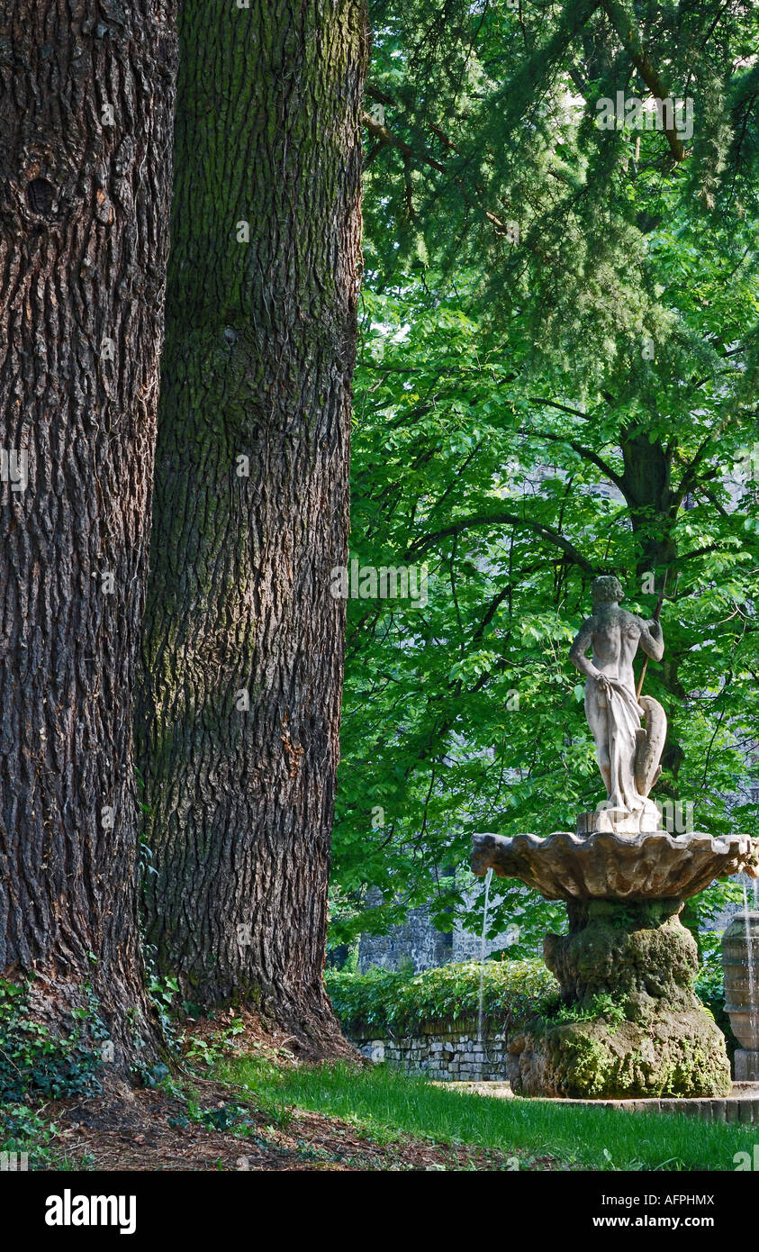 A fountain statue of neptune beside trees in a classic Italian garden ...