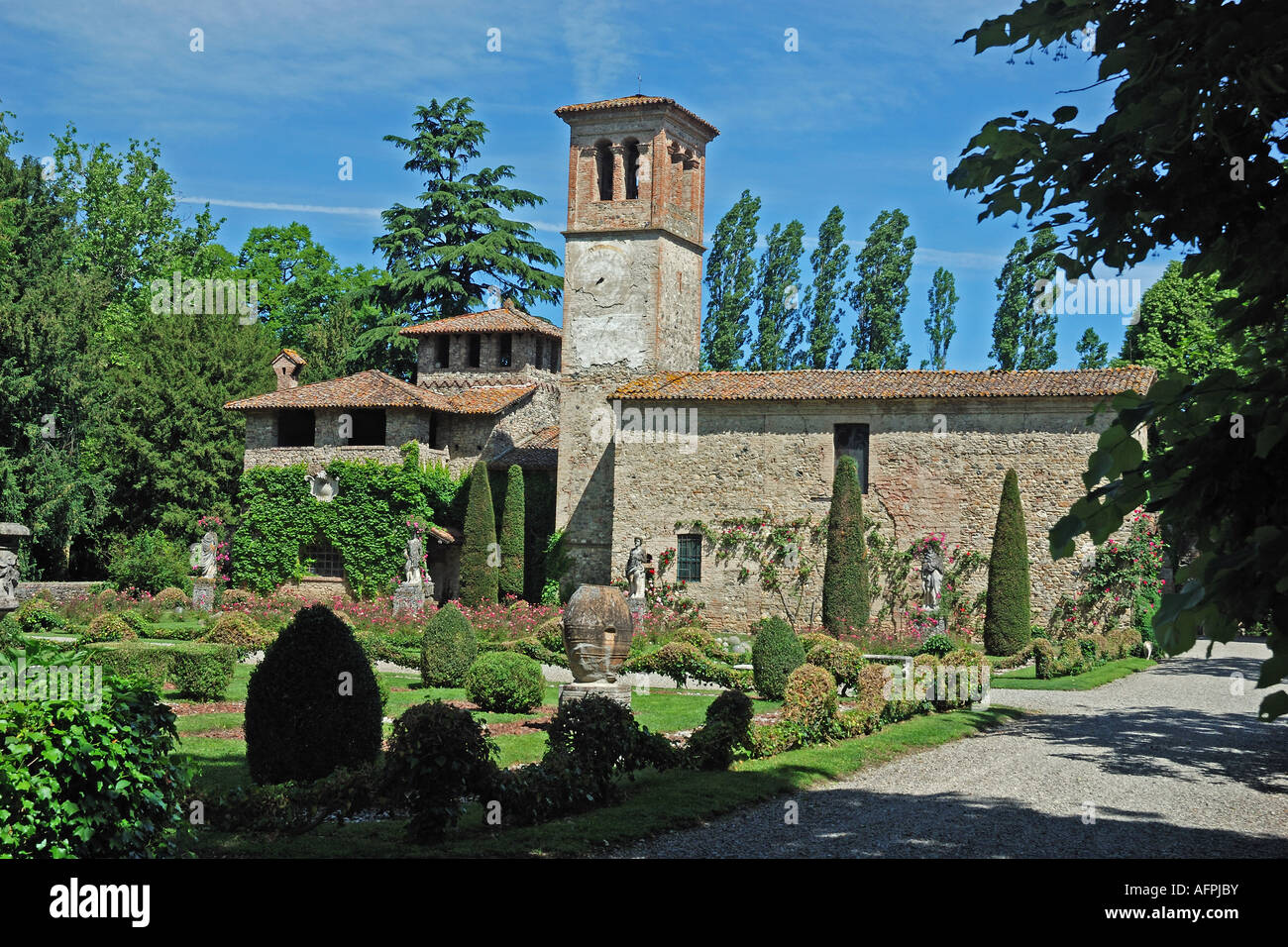 A classic Italian garden with rustic church building in background ...