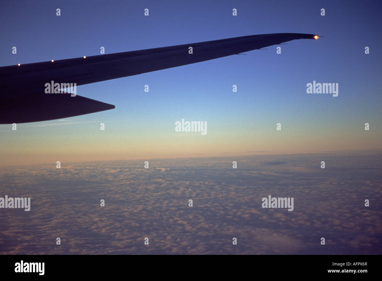 Silhouetted View of Plane Wing with Lights on above Clouds just after ...