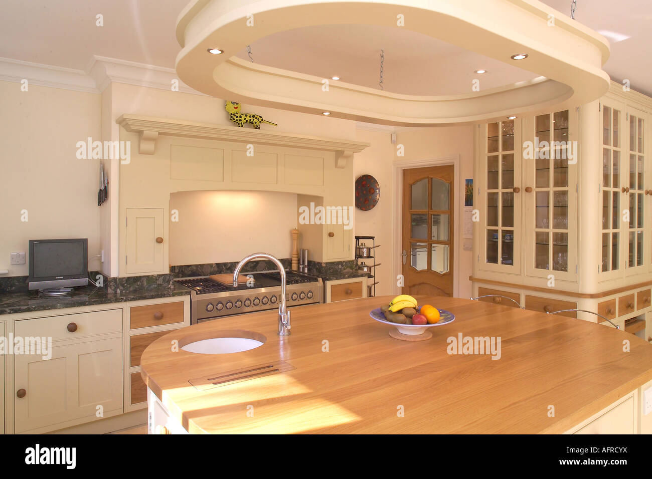 Circular lighting track above beech worktop in modern neutral kitchen ...