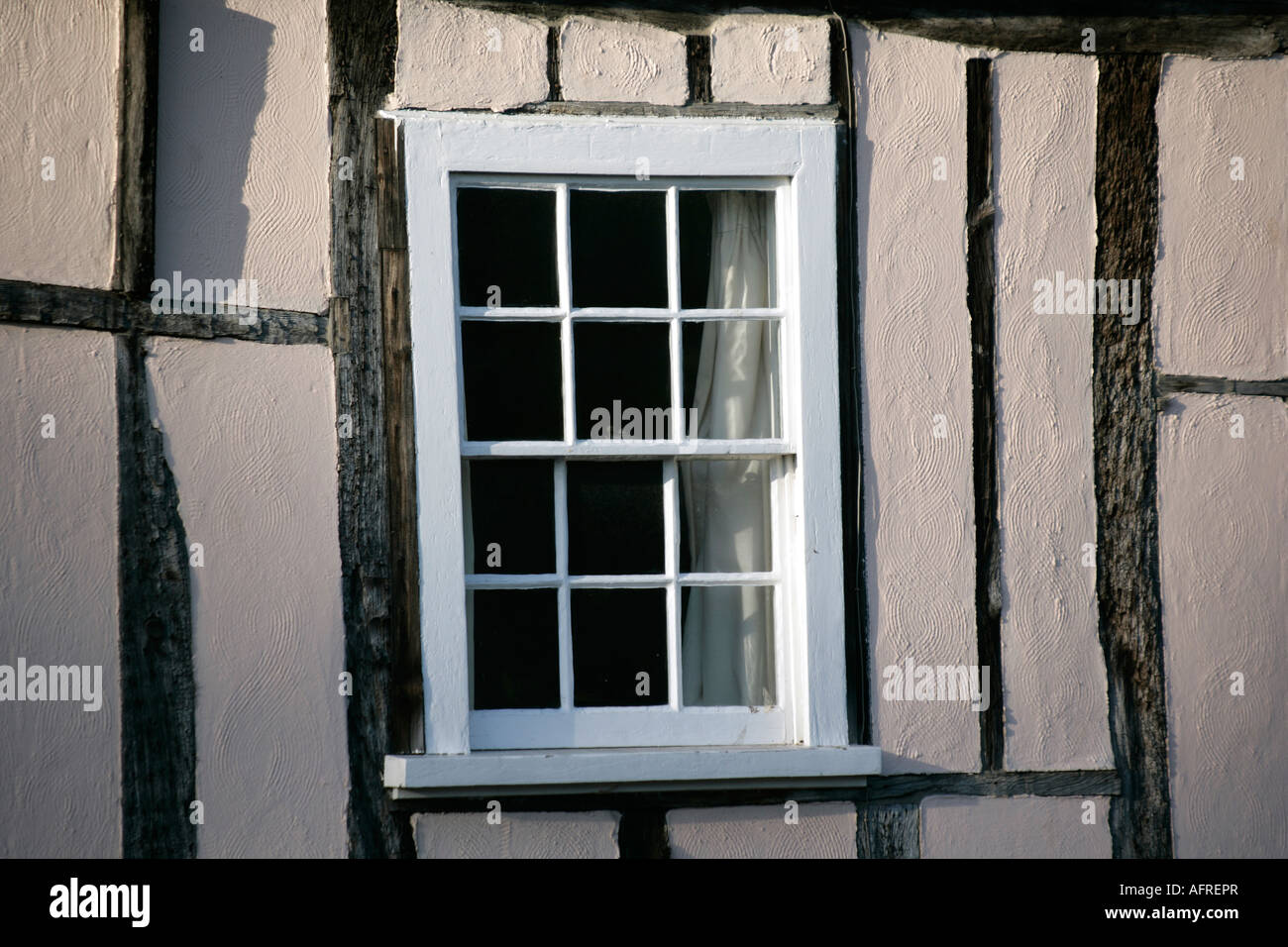 Antique sash window of a timber-framed cottage catching the last sun ...