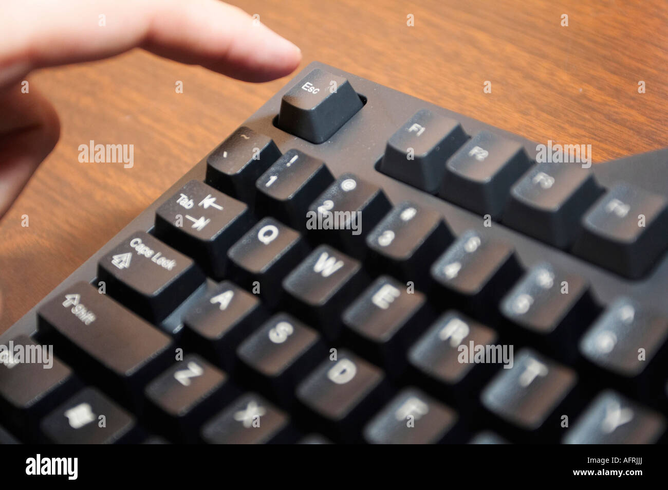 A close up view of a finger pushing the escape button on a keyboard ...