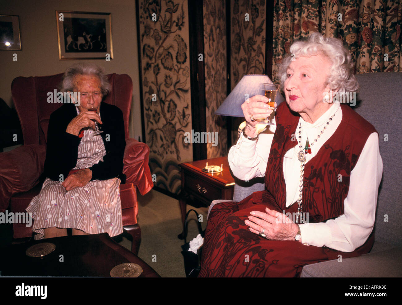 Elderly ladies toast each other drinking a glass of sherry in their ...