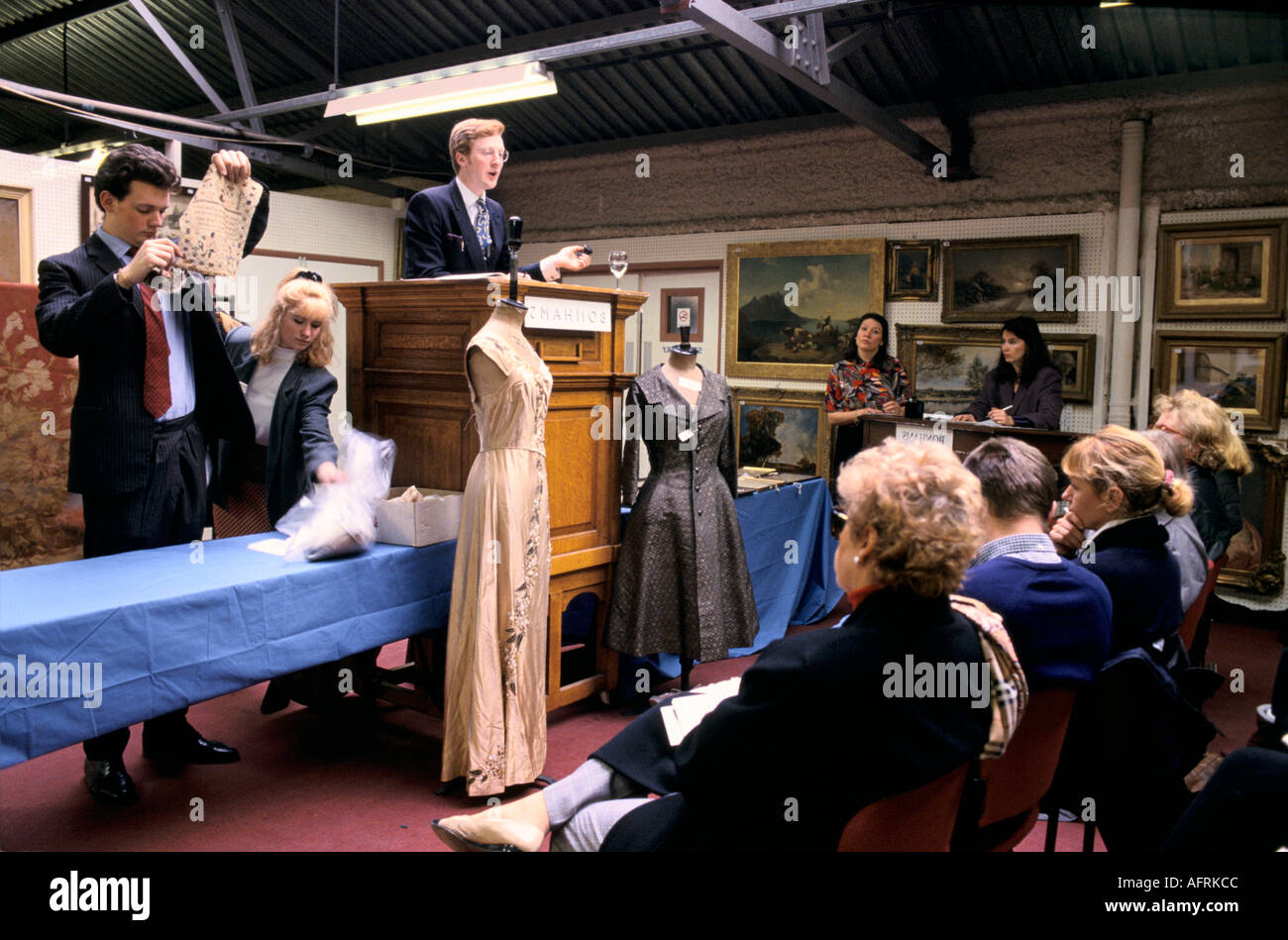 Vintage clothes auction, collectors viewing items being held up by ...