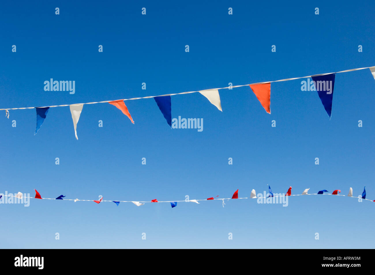 Red white and blue triangular flags fluttering against a clear blue sky ...