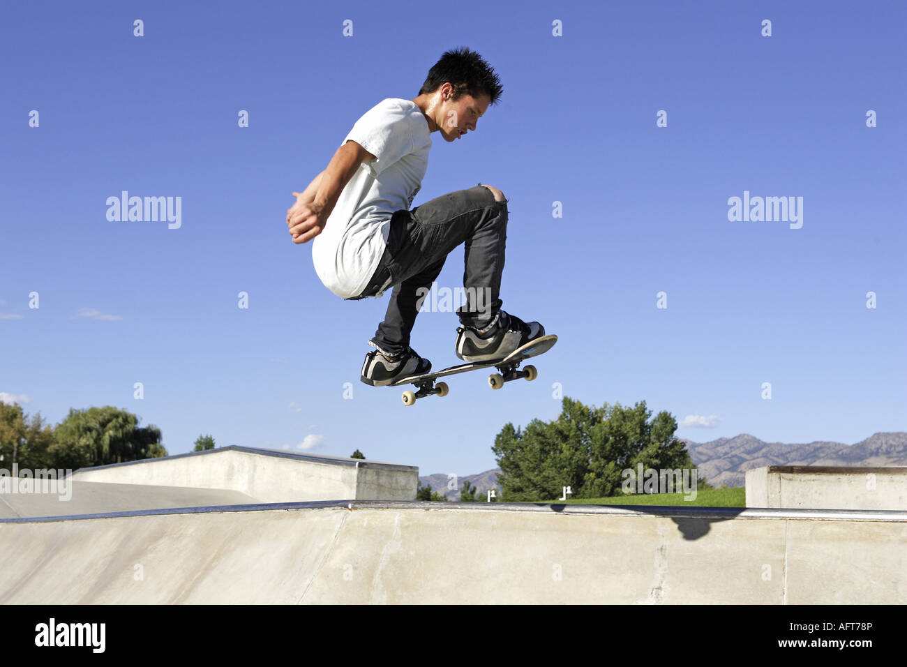 Teenage skateboarder flying high over concrete skate park Stock Photo ...