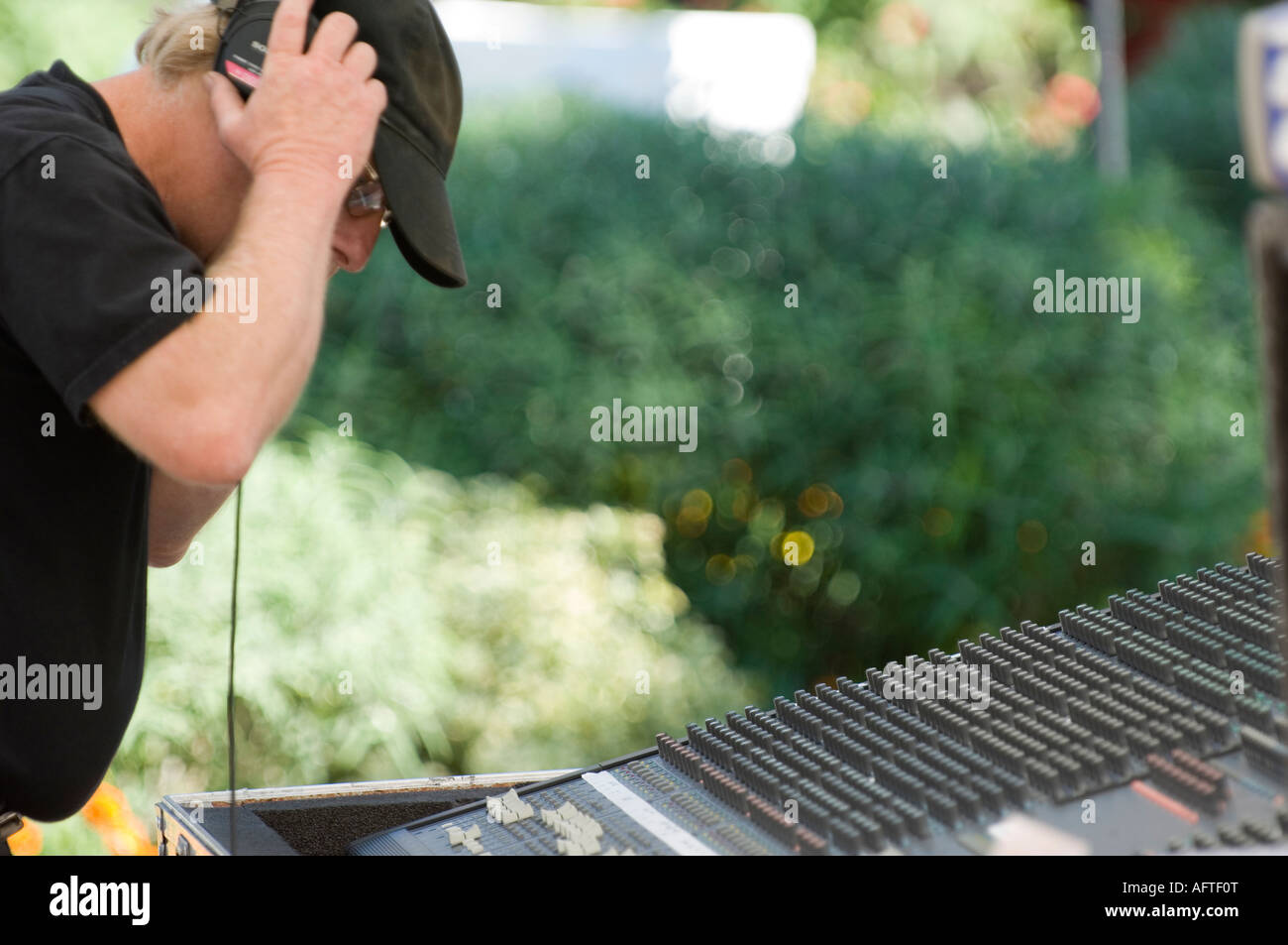 A sound engineer, while adjusting levels for an outdoor concert, puts ...