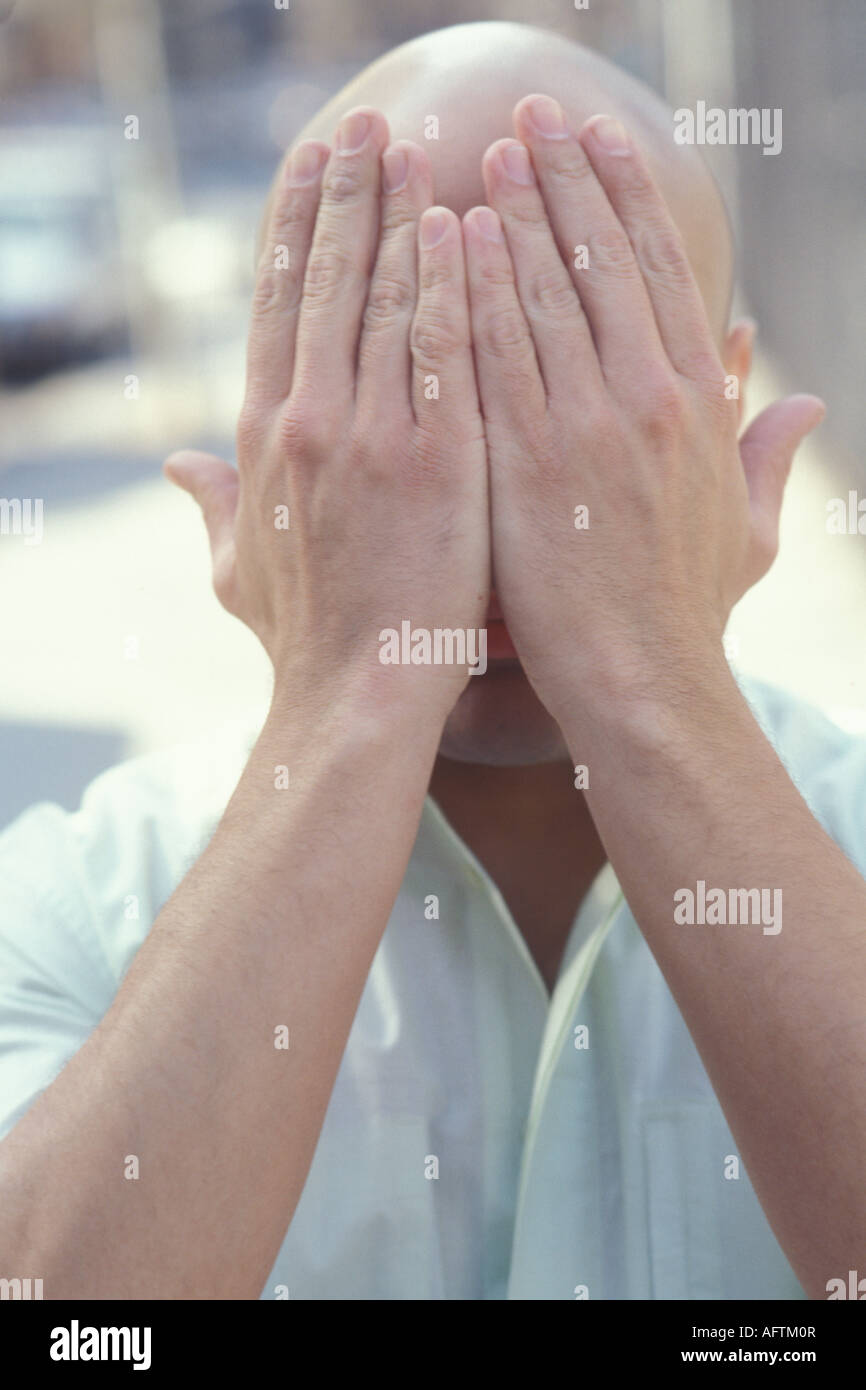 Young man covering face with hands Stock Photo - Alamy