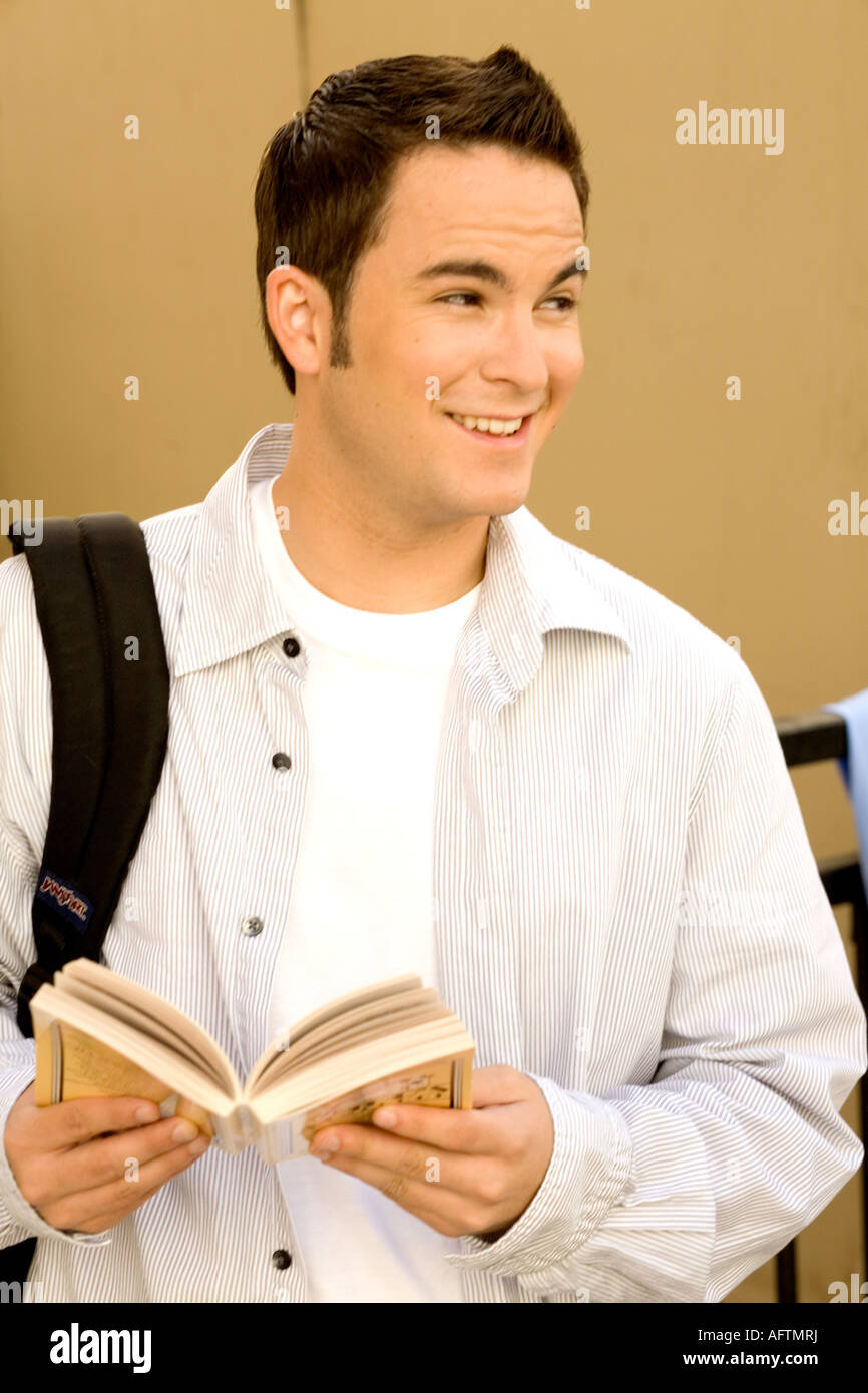 Young man holding bag and book, smiling, portrait Stock Photo - Alamy