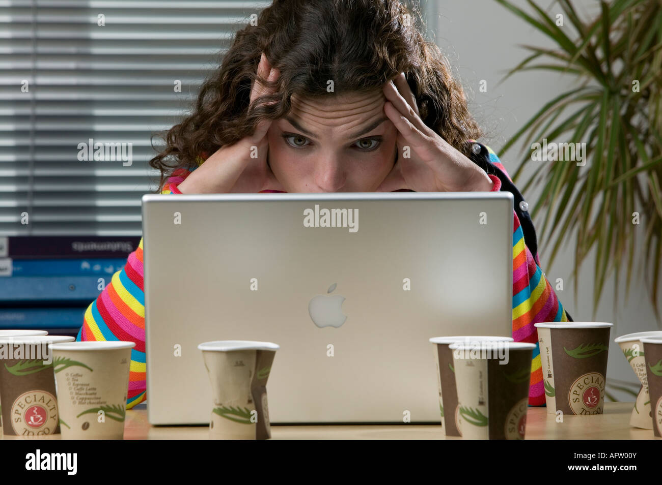 A very frustrated female office worker looking into a laptop screen ...