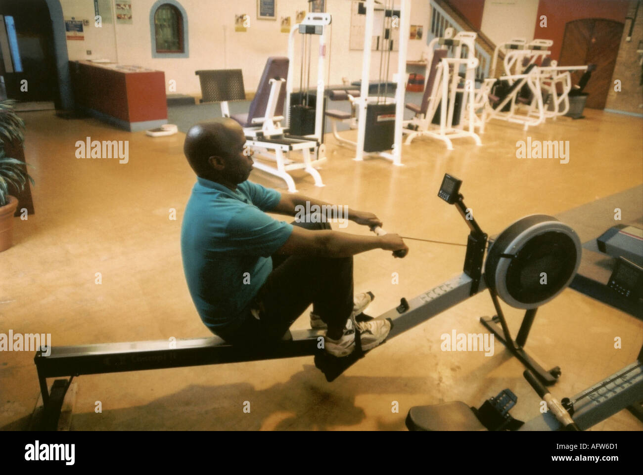 Man exercising on a rowing machine pulling heaving PE PT Shape up adult ...
