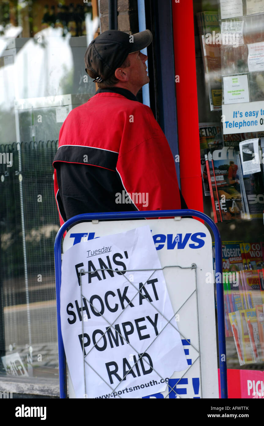 a man in front of fans shock at pompey raid sign looking in news agents ...