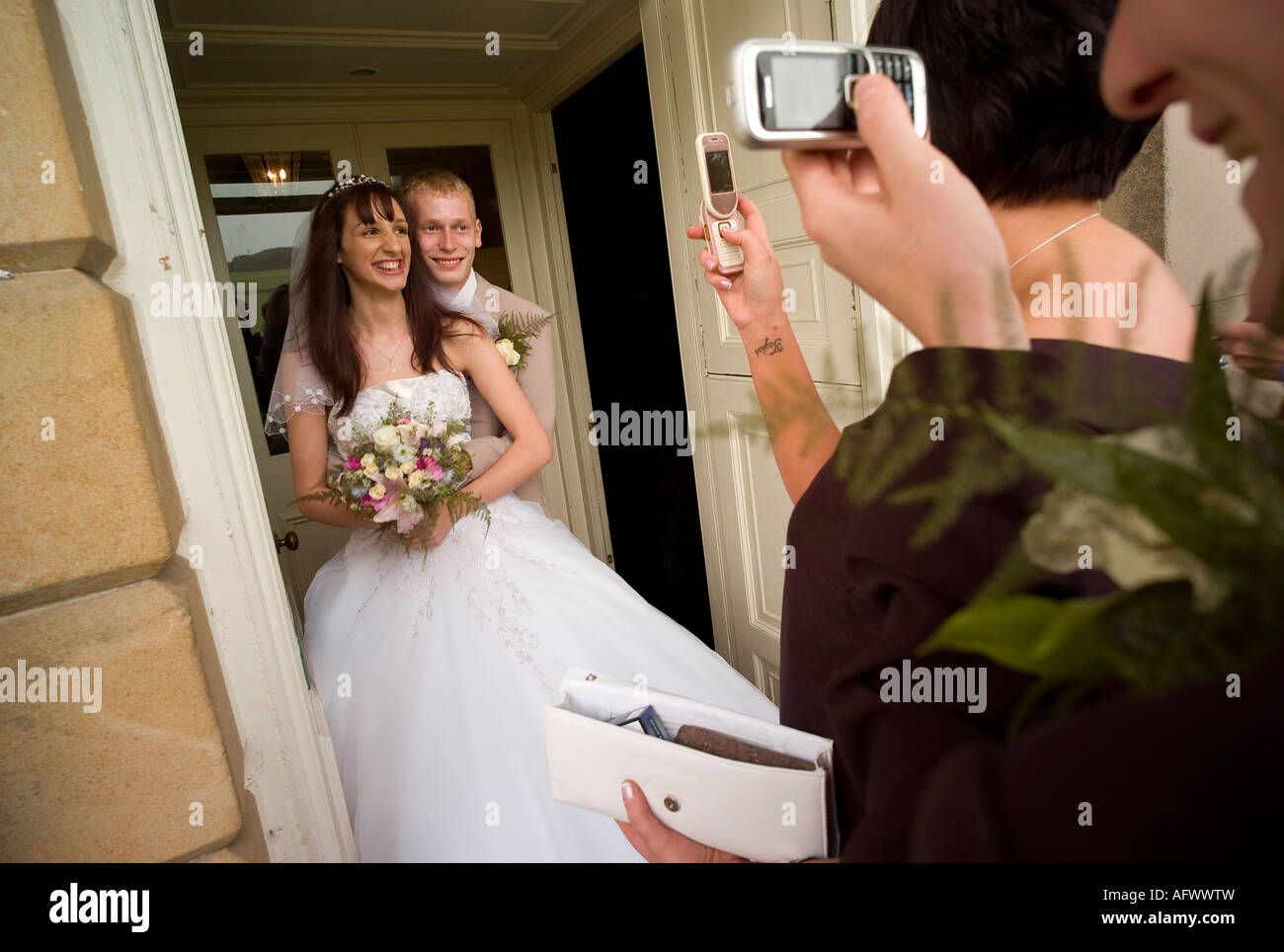 happy smiling bride and groom being photographed on mobile phones at ...