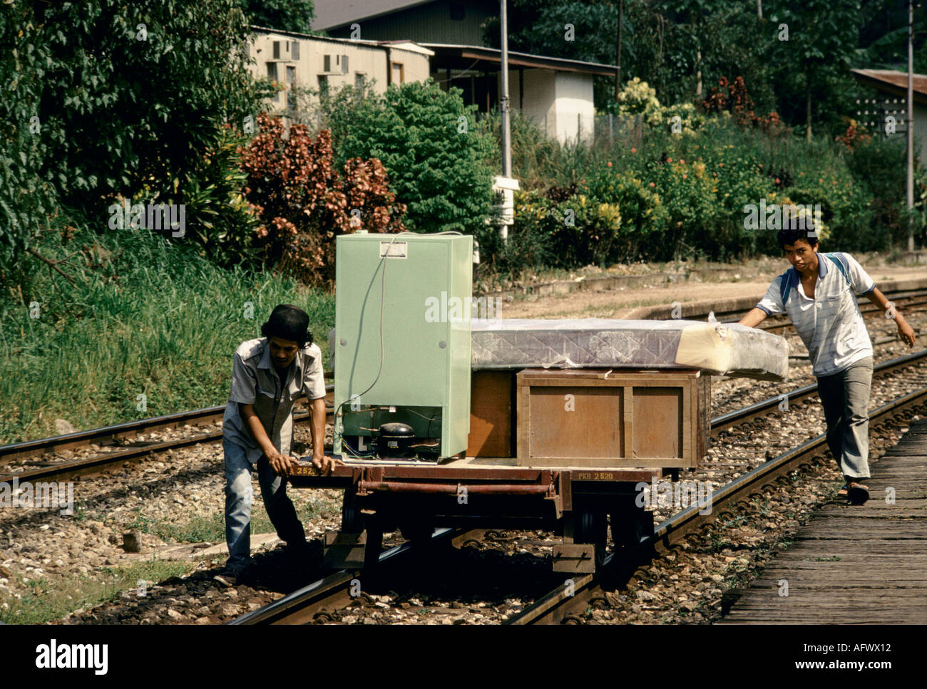 THAILAND MEN MOVING HOUSE ALONG RAIL TRACKS. TWO MEN MOVE THEIR ...