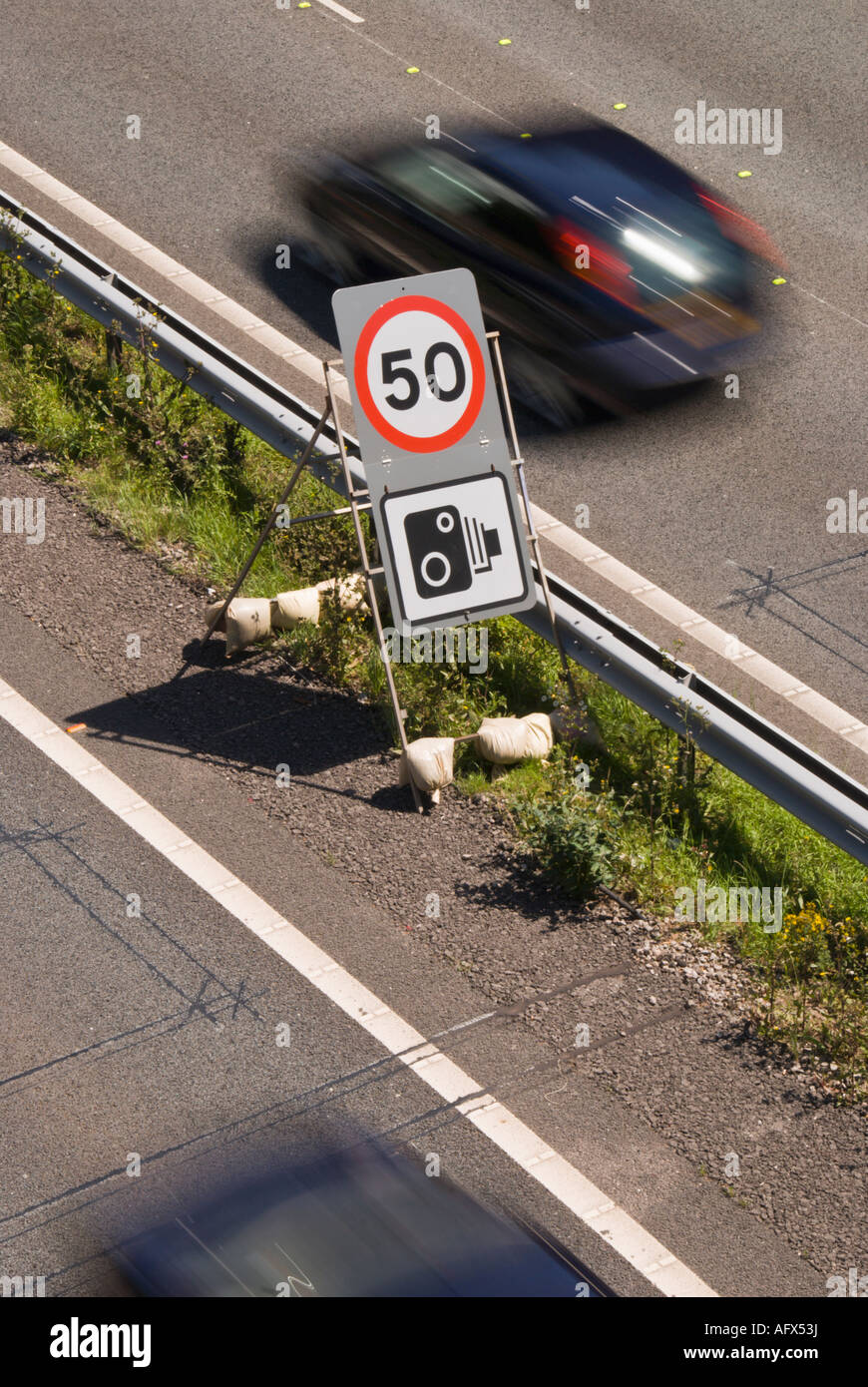 Speeding cars passing a speed limit sign blurred to emphasize motion ...