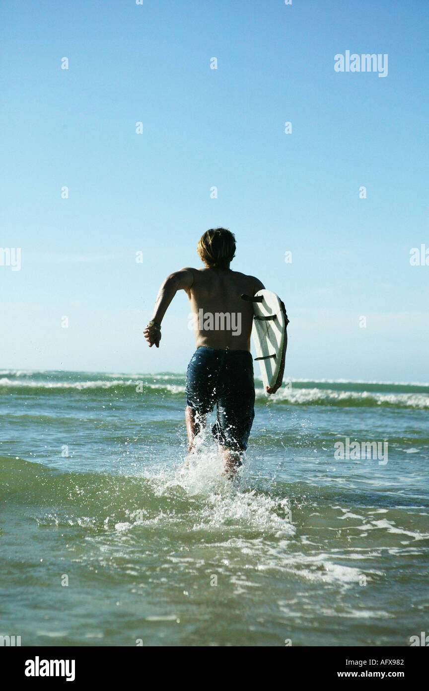 Man running into sea with surfboard Stock Photo - Alamy