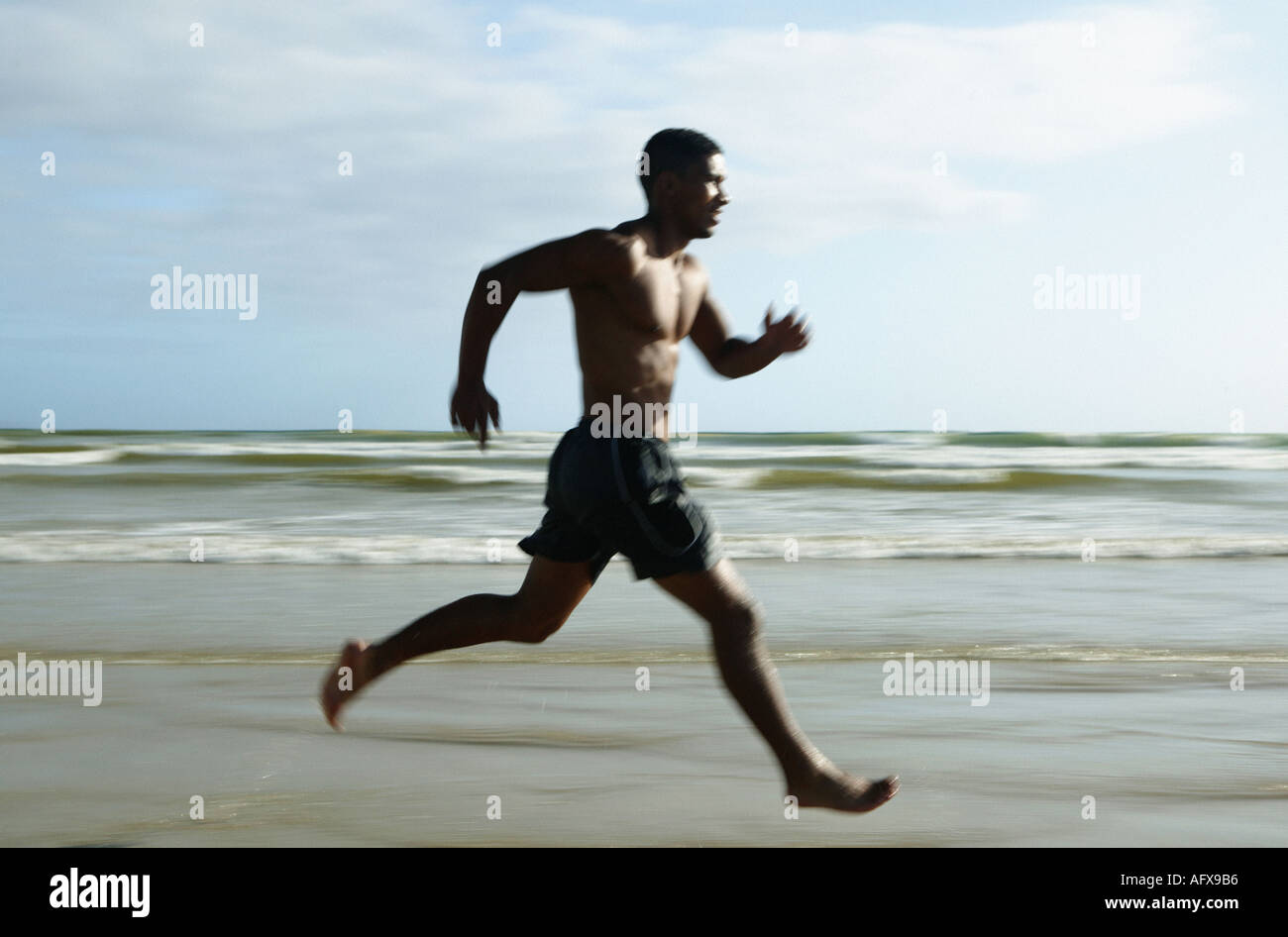 Man running on beach Stock Photo - Alamy