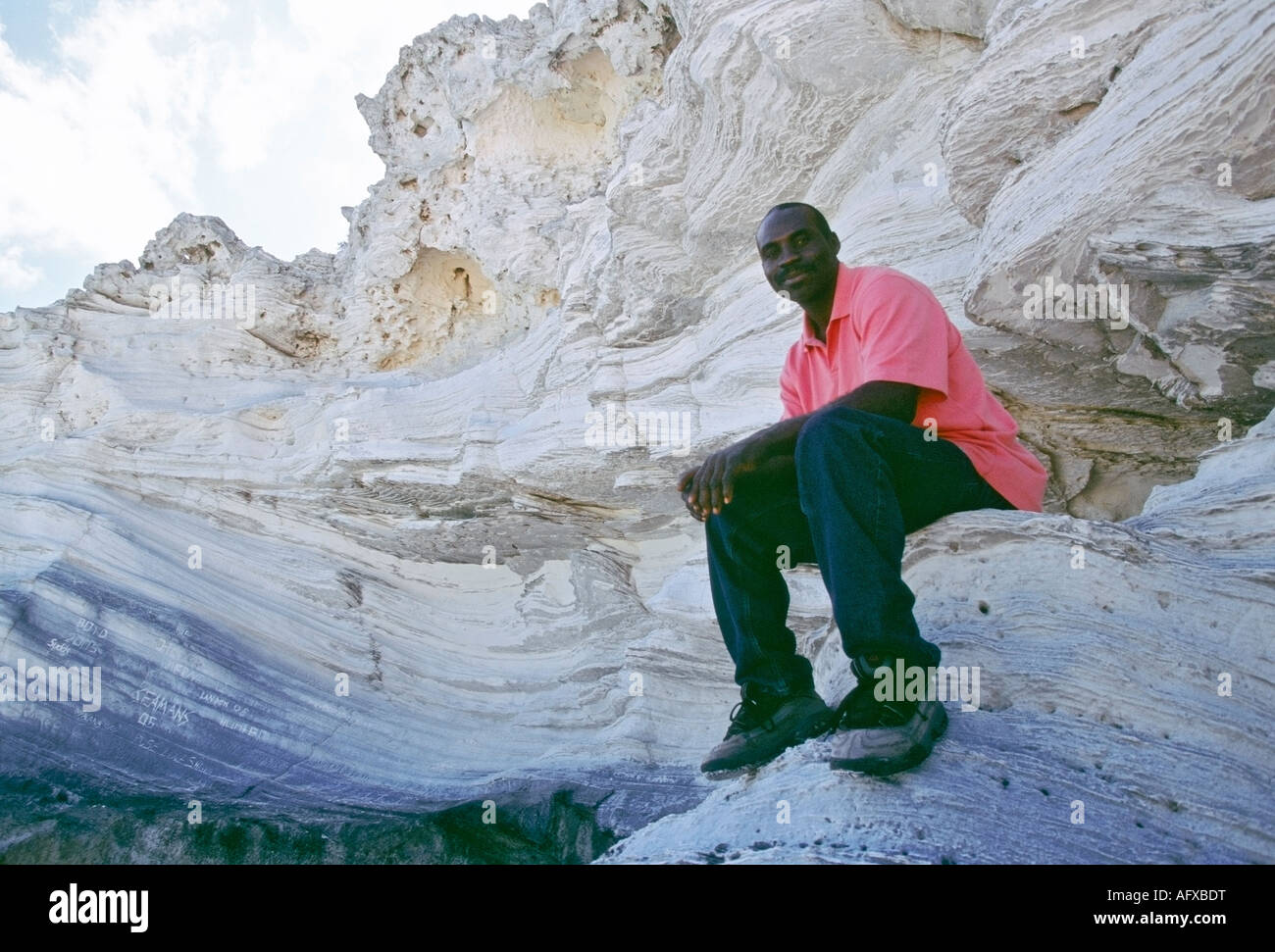 Bahamian man on a rocky cliff near the beach on the island of Eleuthera ...