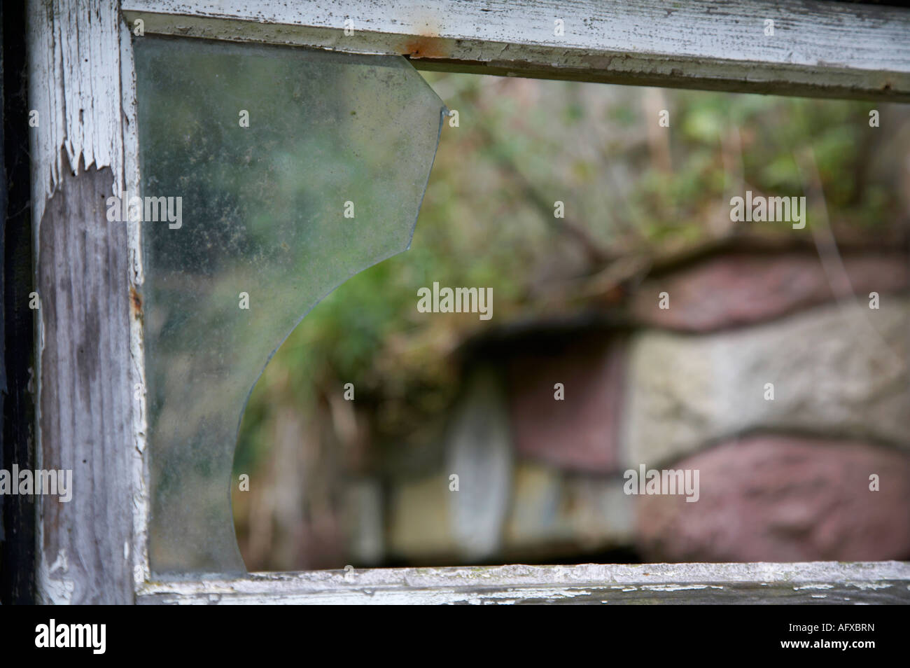 broken window pane in weathered wooden frame looking in to abandoned ...