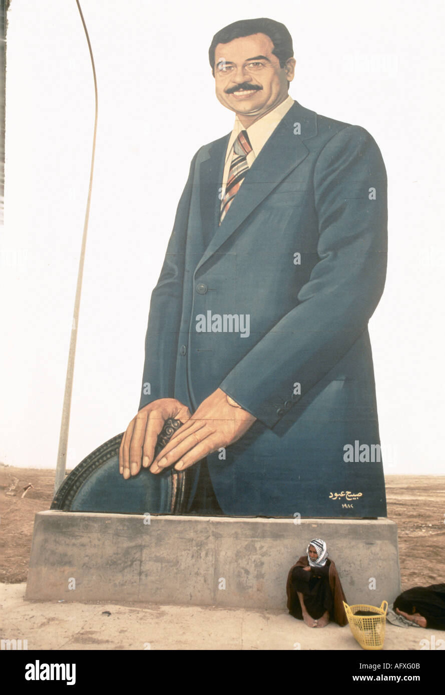 Saddam Hussein man sitting in the shade under a giant poster of Saddam ...