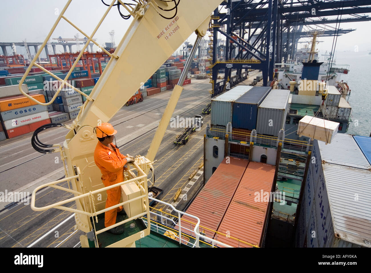 Container ship crew using boom crane to load supplies onto ship at Hong ...
