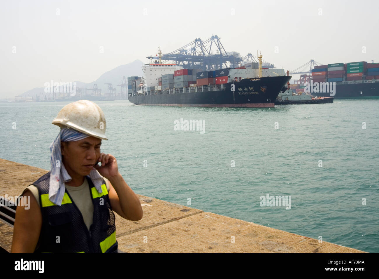 Container ship longshoreman talks on moblie phone while waiting for ...