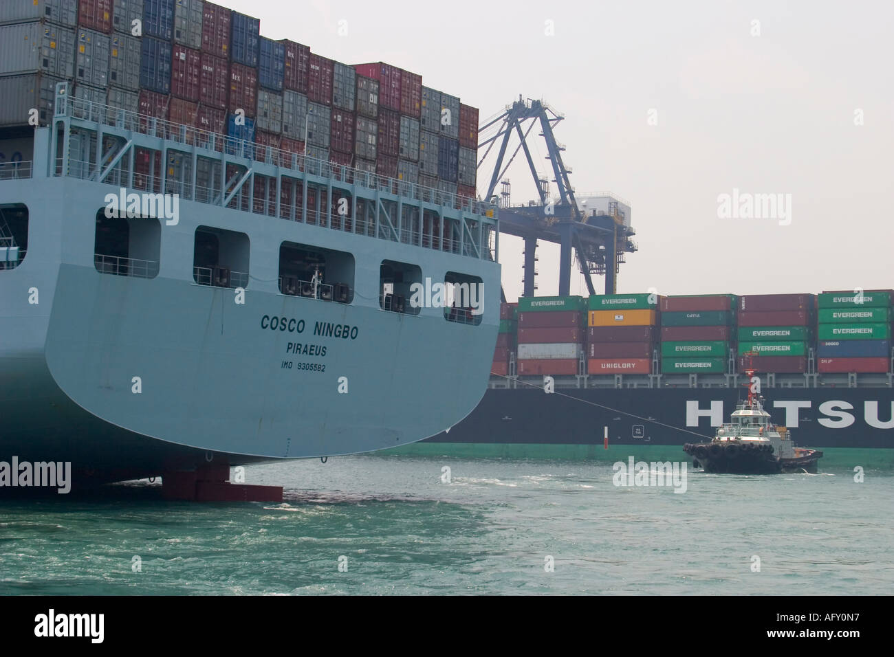 Tug boat assists massive container ship pulling away from dock to clear ...