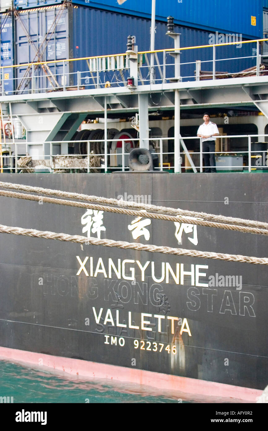 Ship cadet stands on the stern of container ship with name of ship and ...