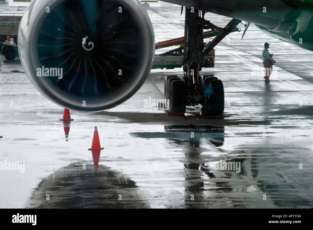 Airport worker on tarmac in rain beneath jet airliner, Taipei, Taiwan ...
