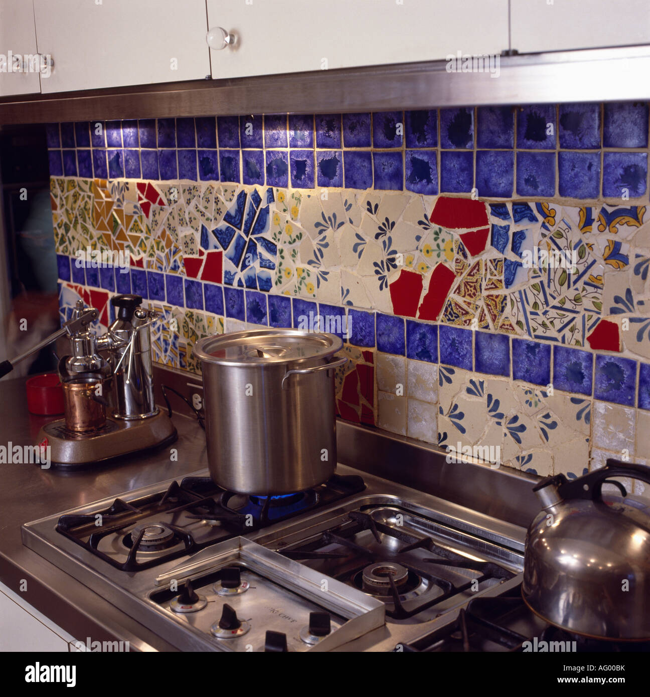 Close up of blue tiles with mosaic tiling above stainless steel pans on ...