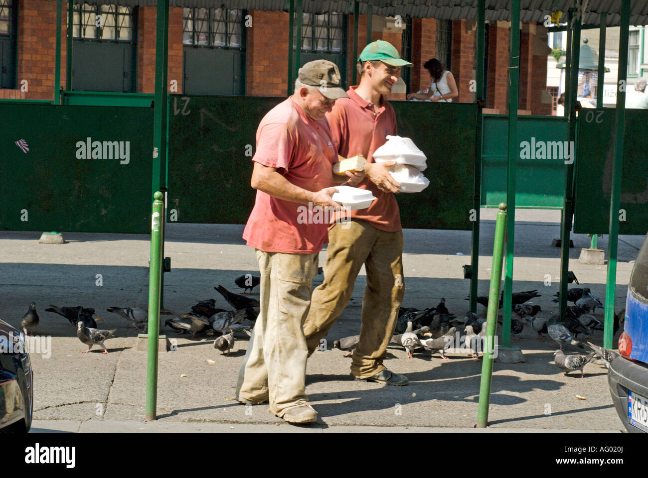 Two Polish working men walking through a covered street market carrying ...