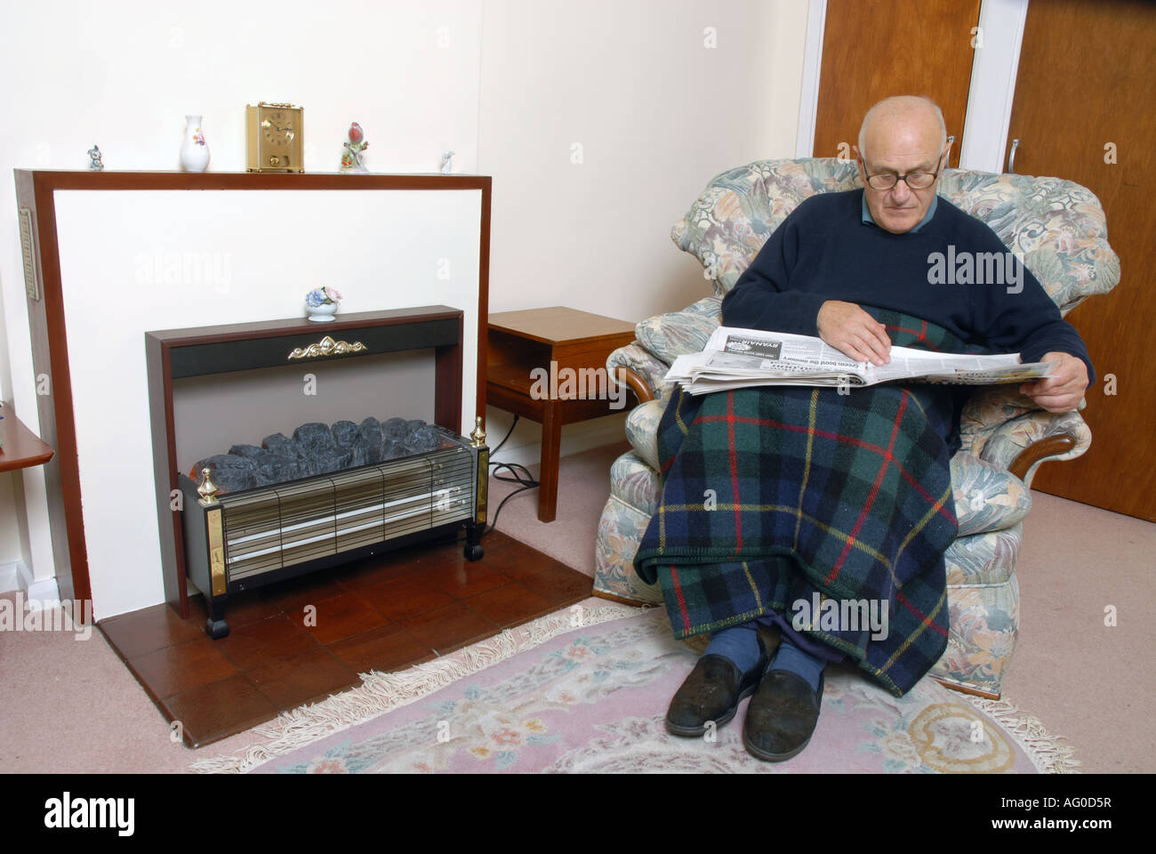 A elderly man sitting infront of his unlit electric fire Stock Photo ...