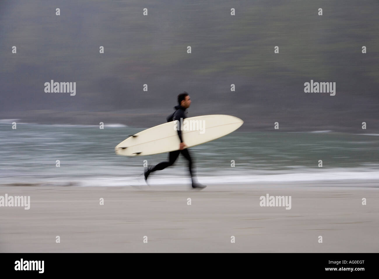 A surfer, running with board along the shoreline Stock Photo - Alamy