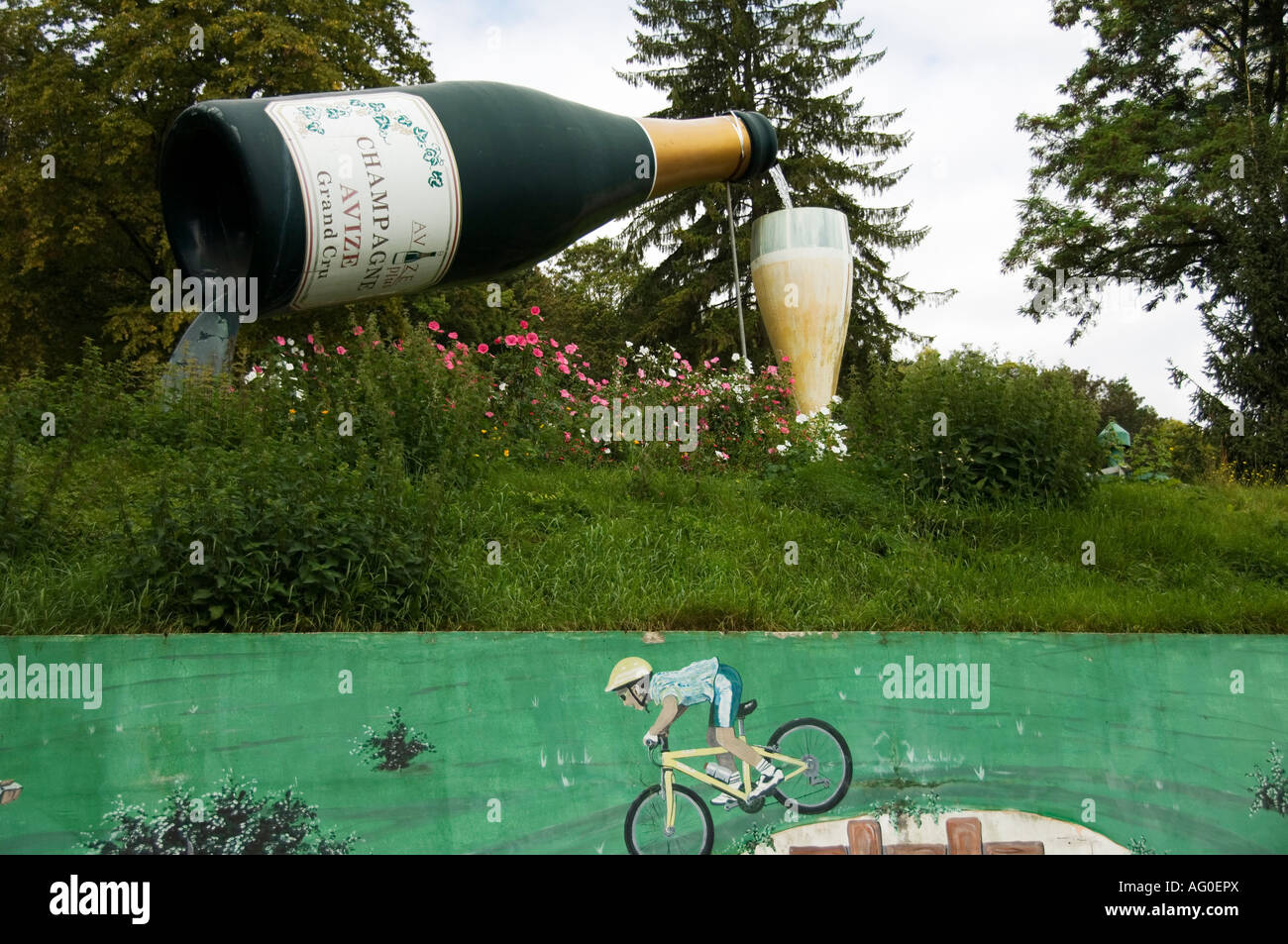 giant champagne bottle pouring into a wine glass on hillside above ...