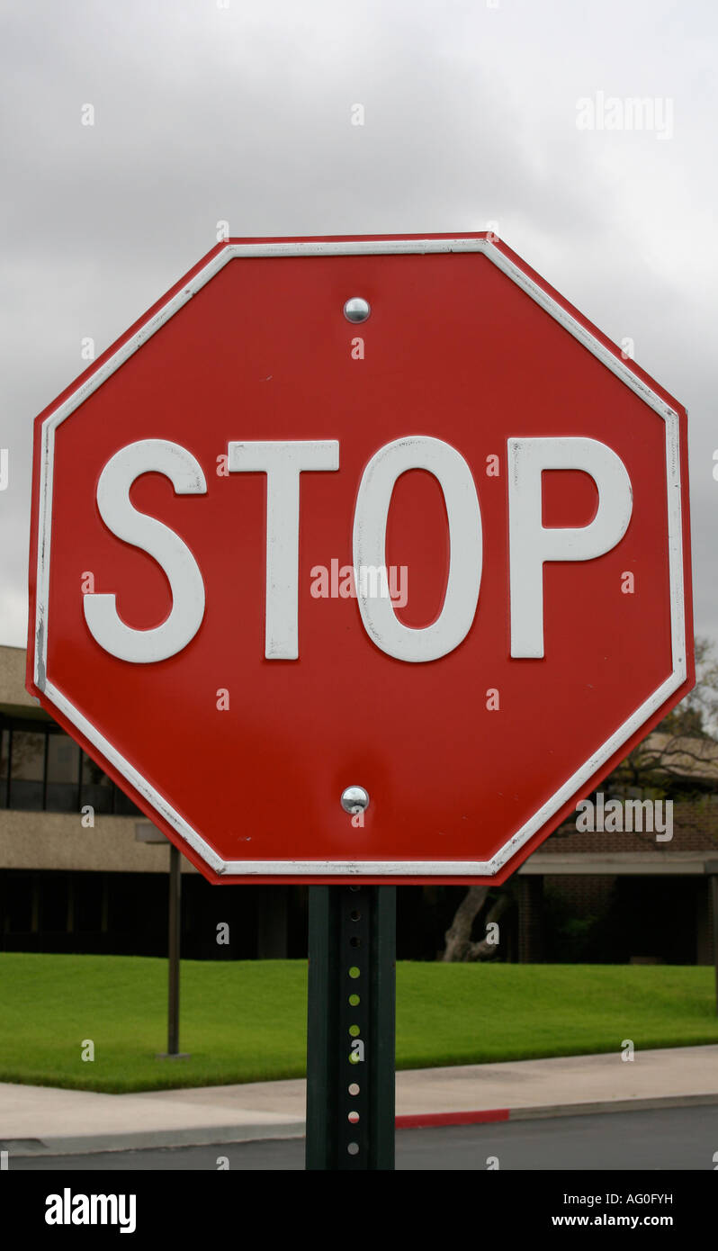 Bright red and white stop sign close up with green grass and beige ...