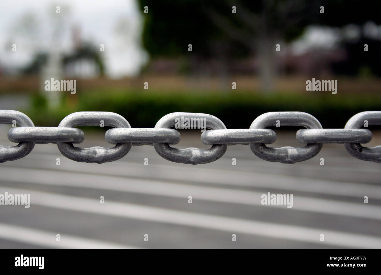 Chain link close up with green blurred and asphalt background Stock ...