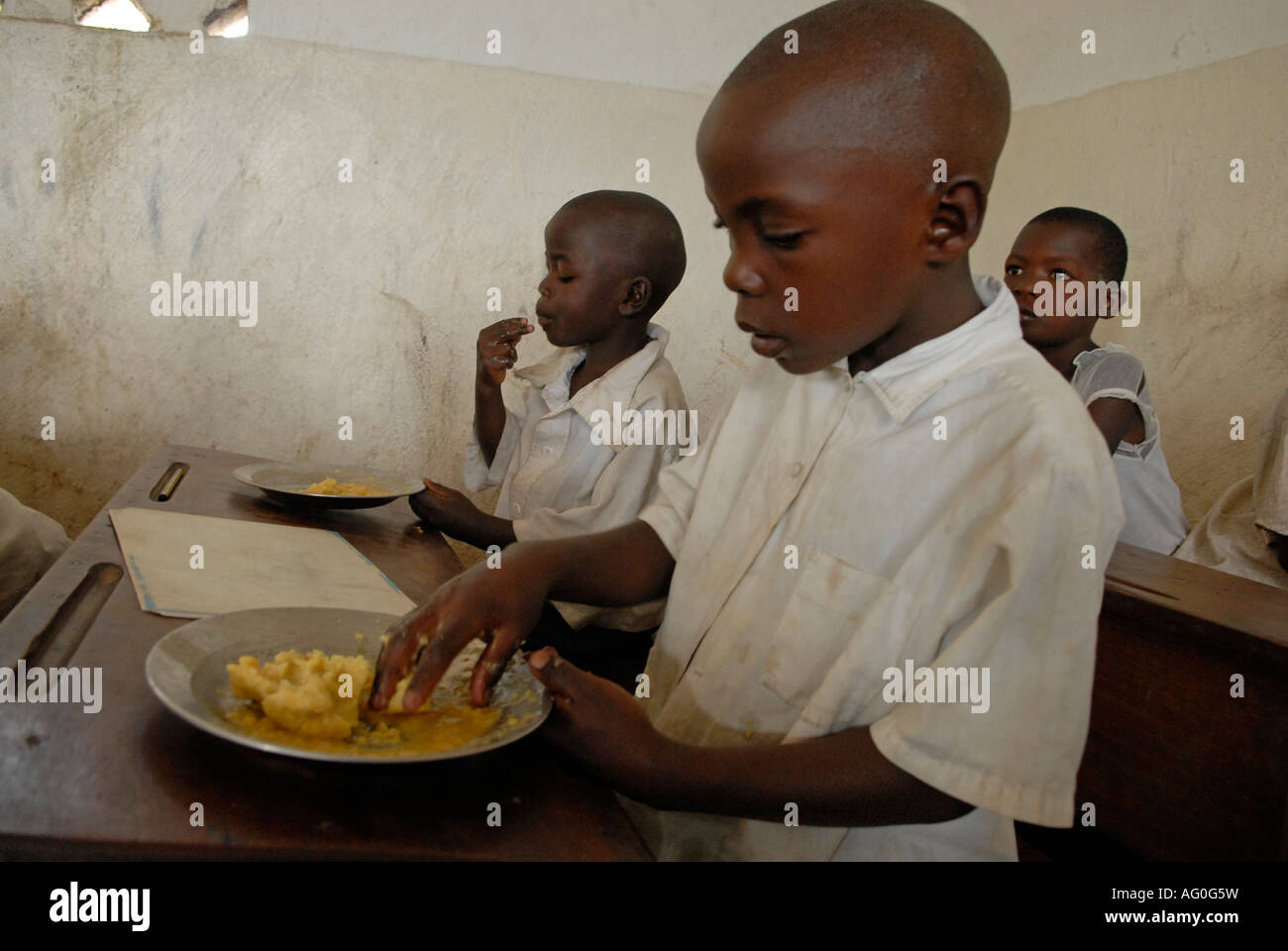 Schoolchildren eating with their hands at lunch time in a primary ...