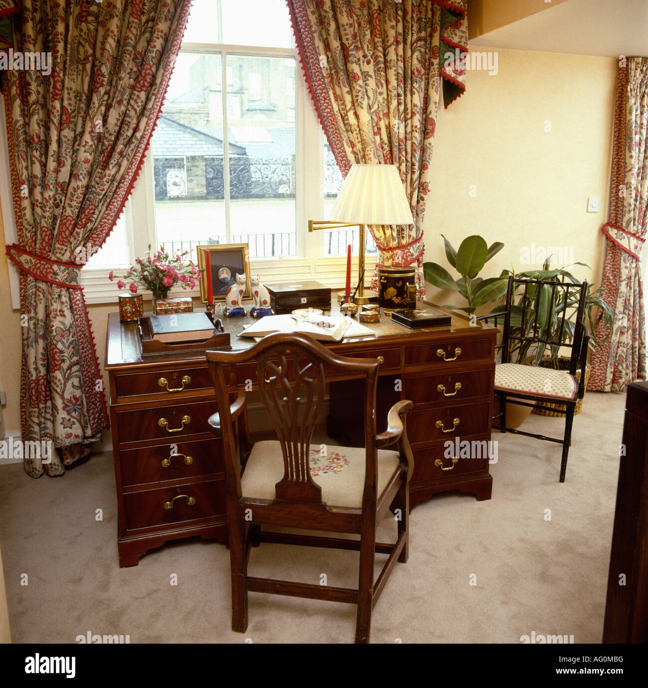 Lighted lamp on antique desk and chair in front of window with ...