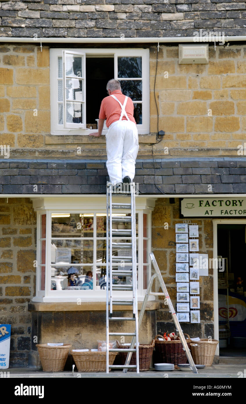 Man painting shop window in Broadway Worcestershire England UK Stock ...