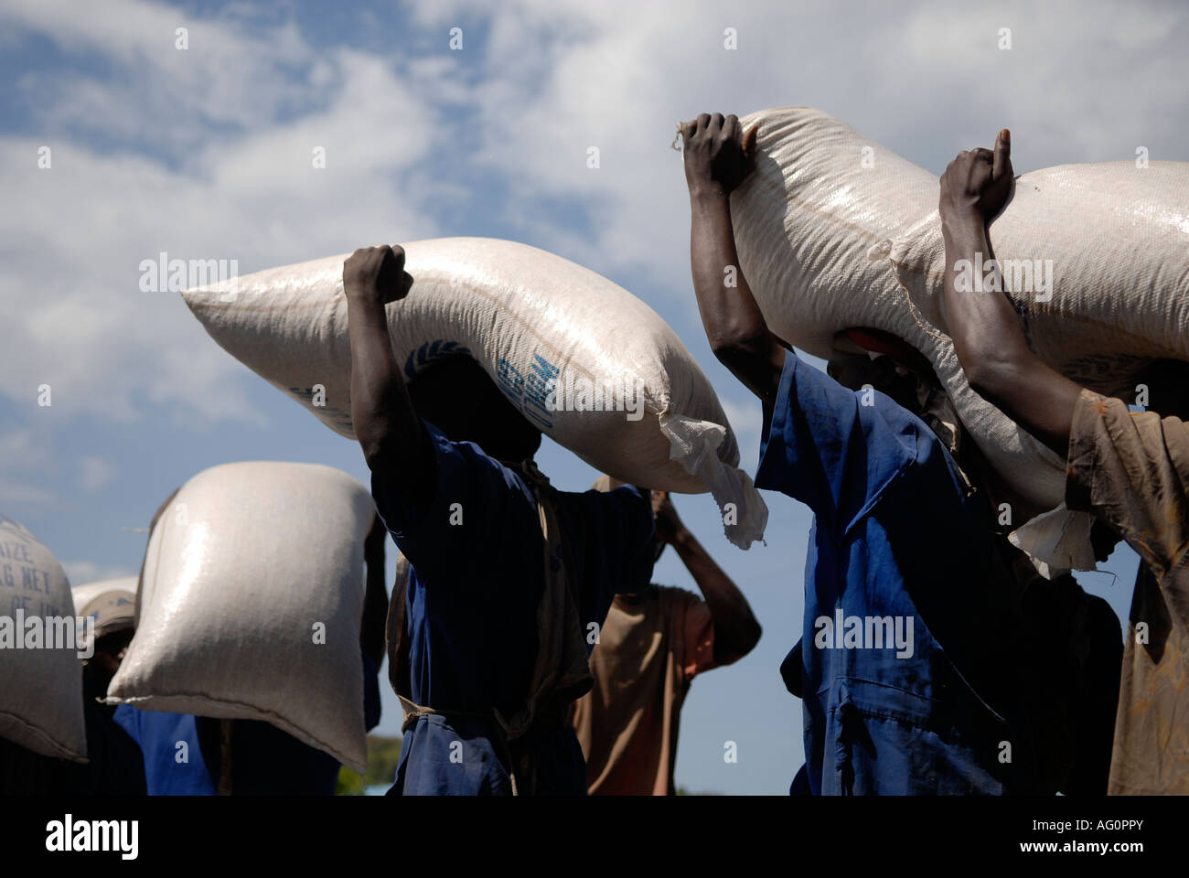 Men carrying large sacks of corn soya blend at a World Food Programme ...