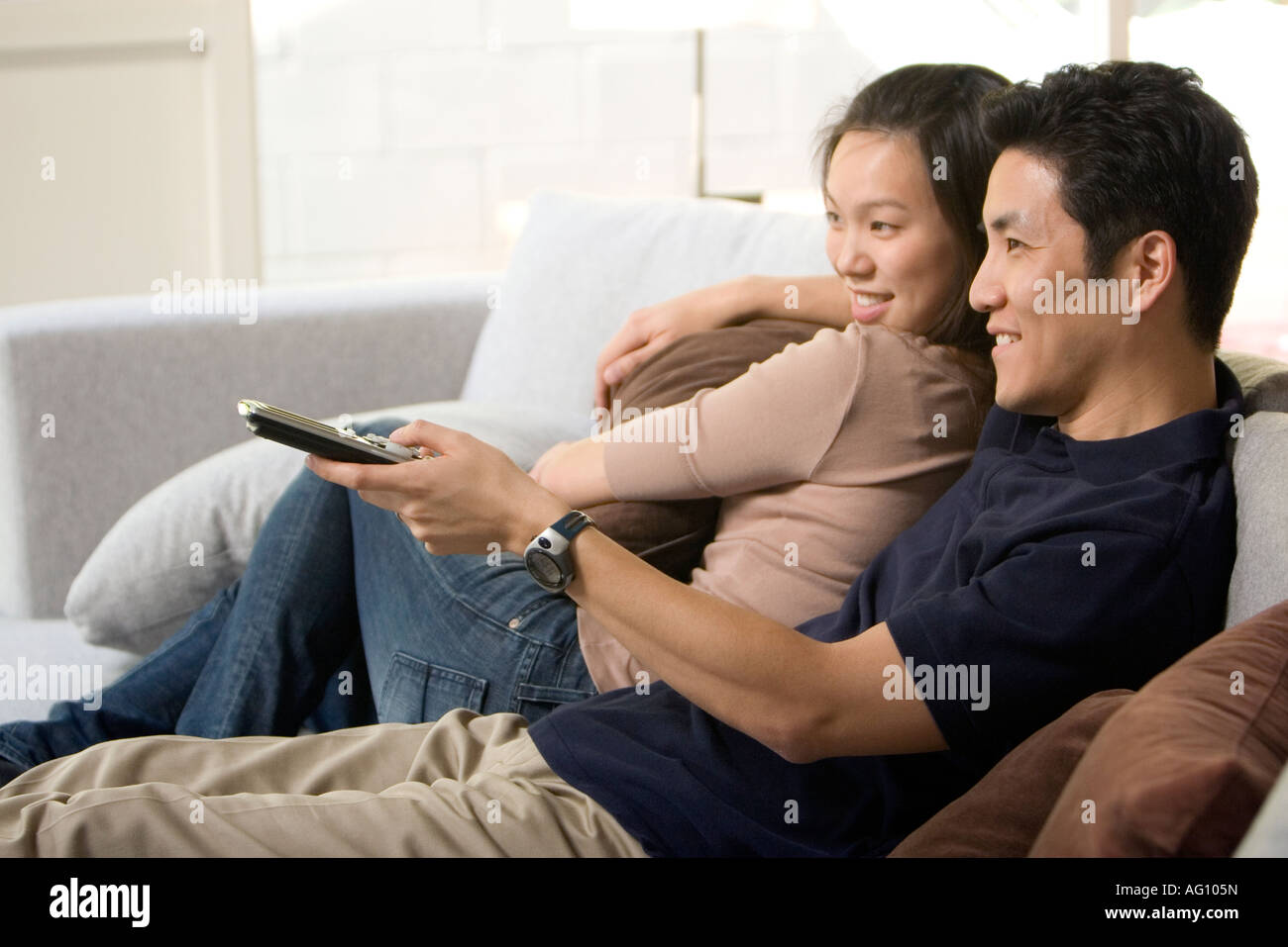 Asian Couple Watching Television Together in Their Modern Home Stock ...