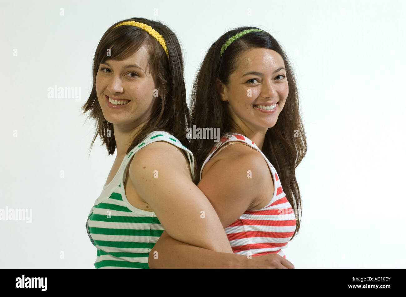 Two smiling young attractive women interlock arms Stock Photo - Alamy