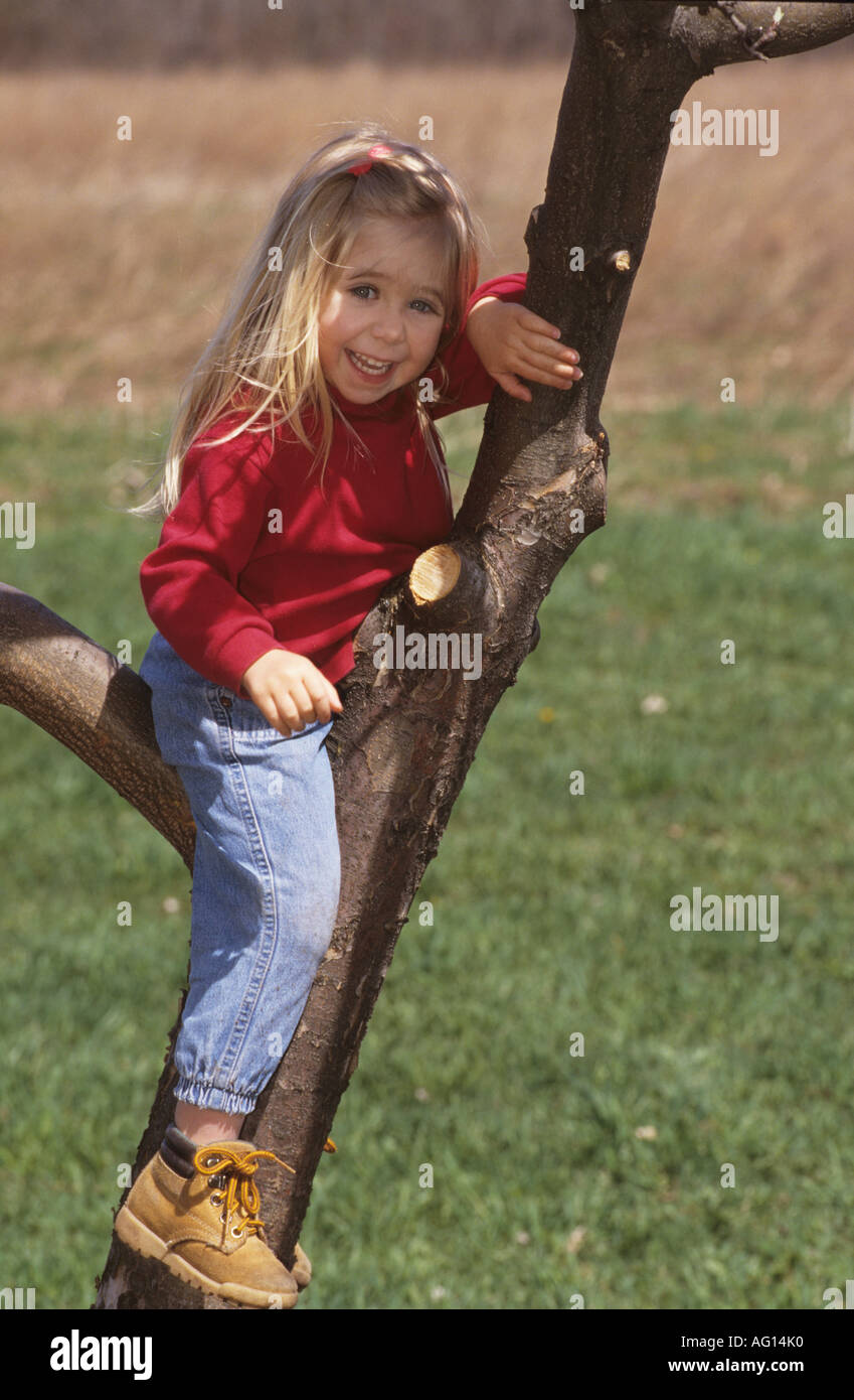 Little girl sitting on tree Stock Photo - Alamy