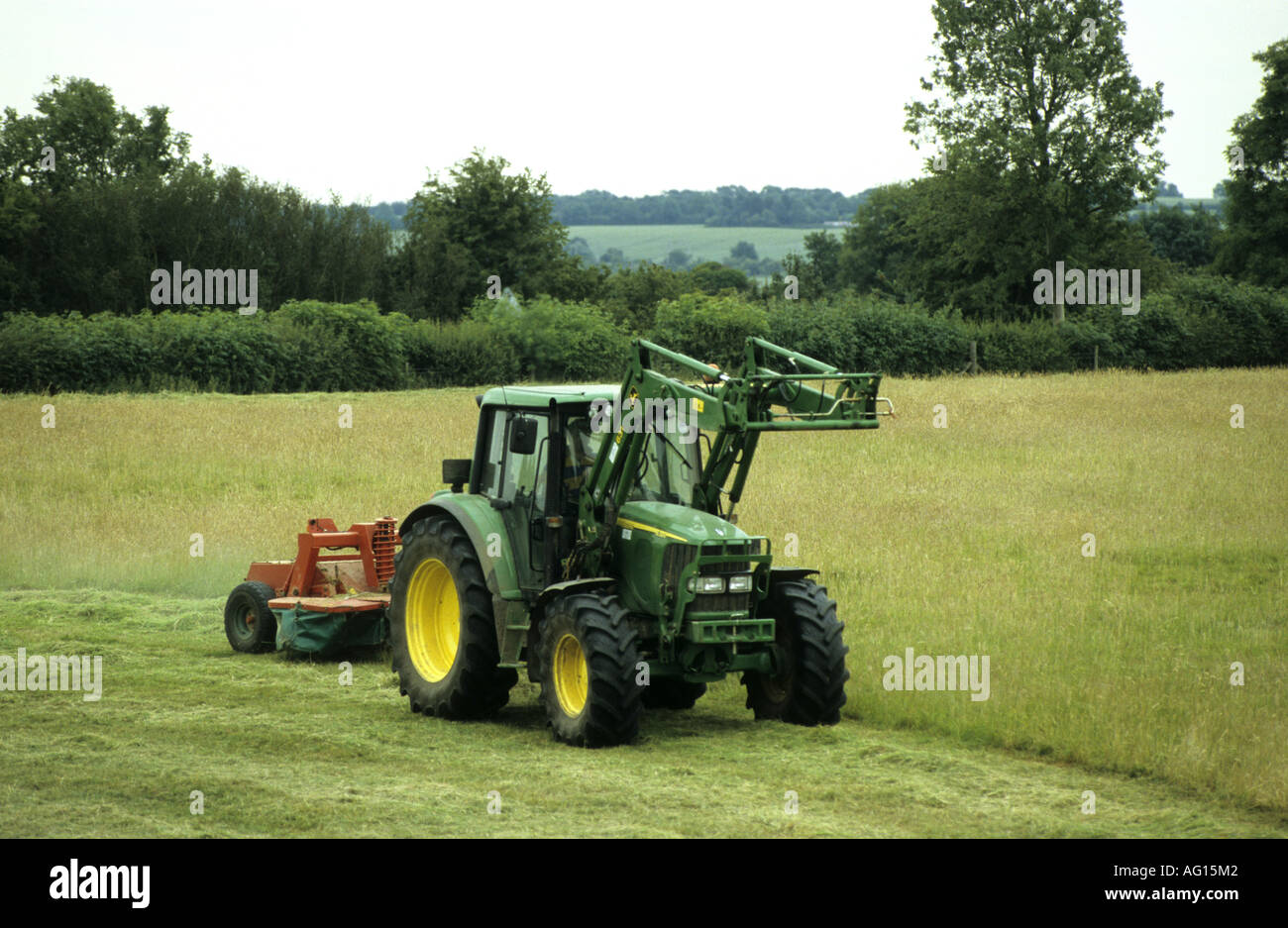John Deere tractor cutting hay field in summer, Northamptonshire ...