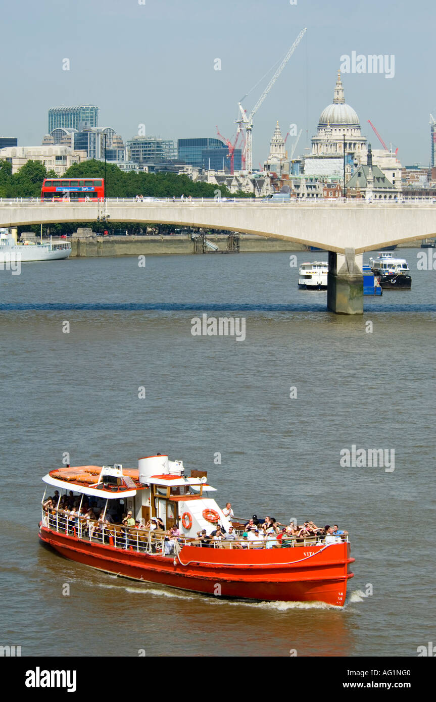 A pleasure boat with tourists has just passed Waterloo bridge with a ...