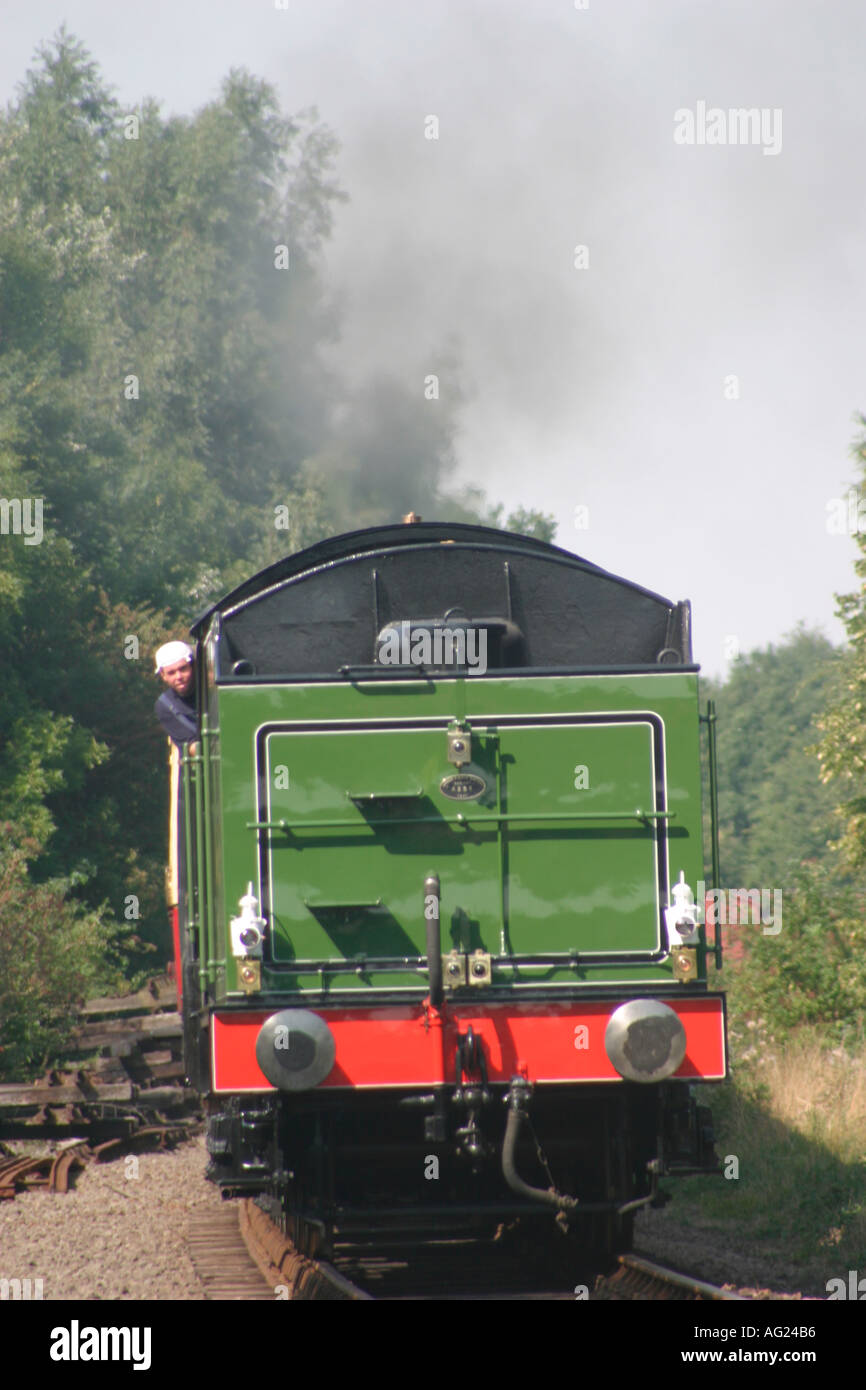Steam train reversing on track with driver looking out of cab, with ...