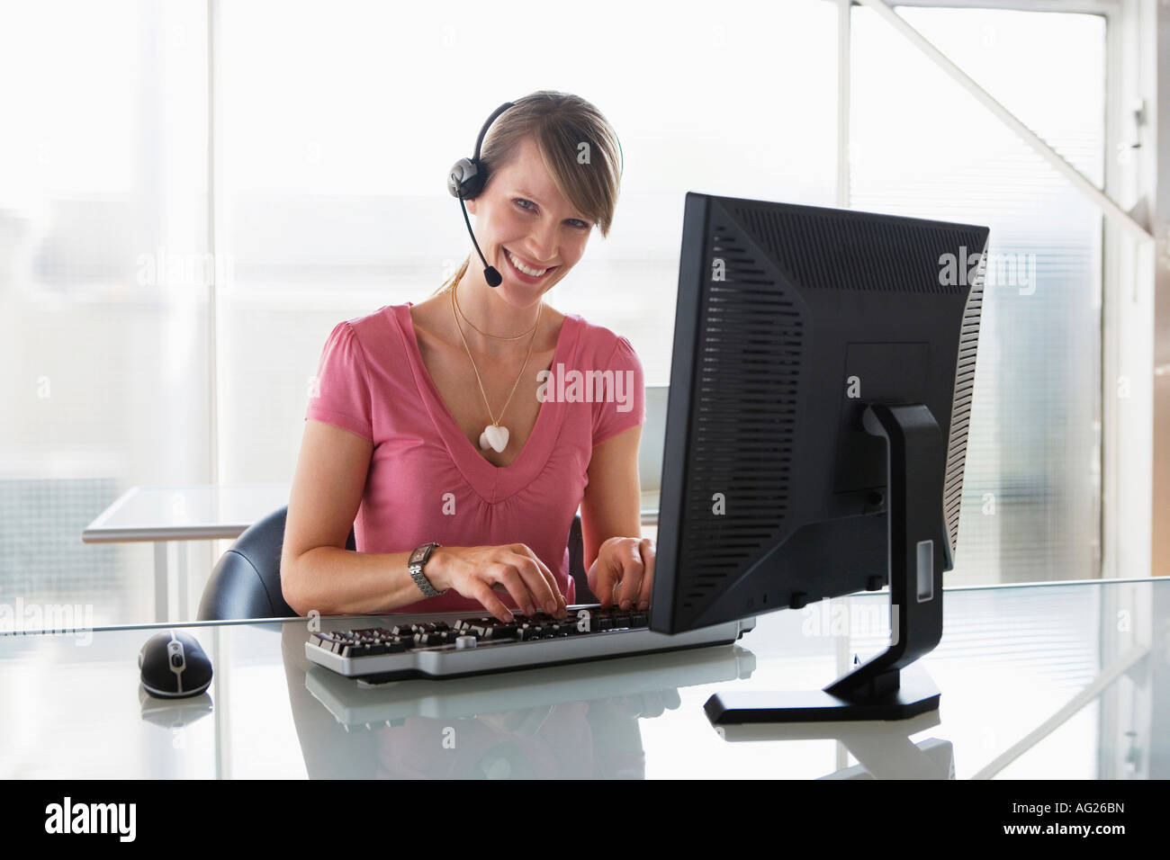 Woman working on computer, wearing headset Stock Photo - Alamy