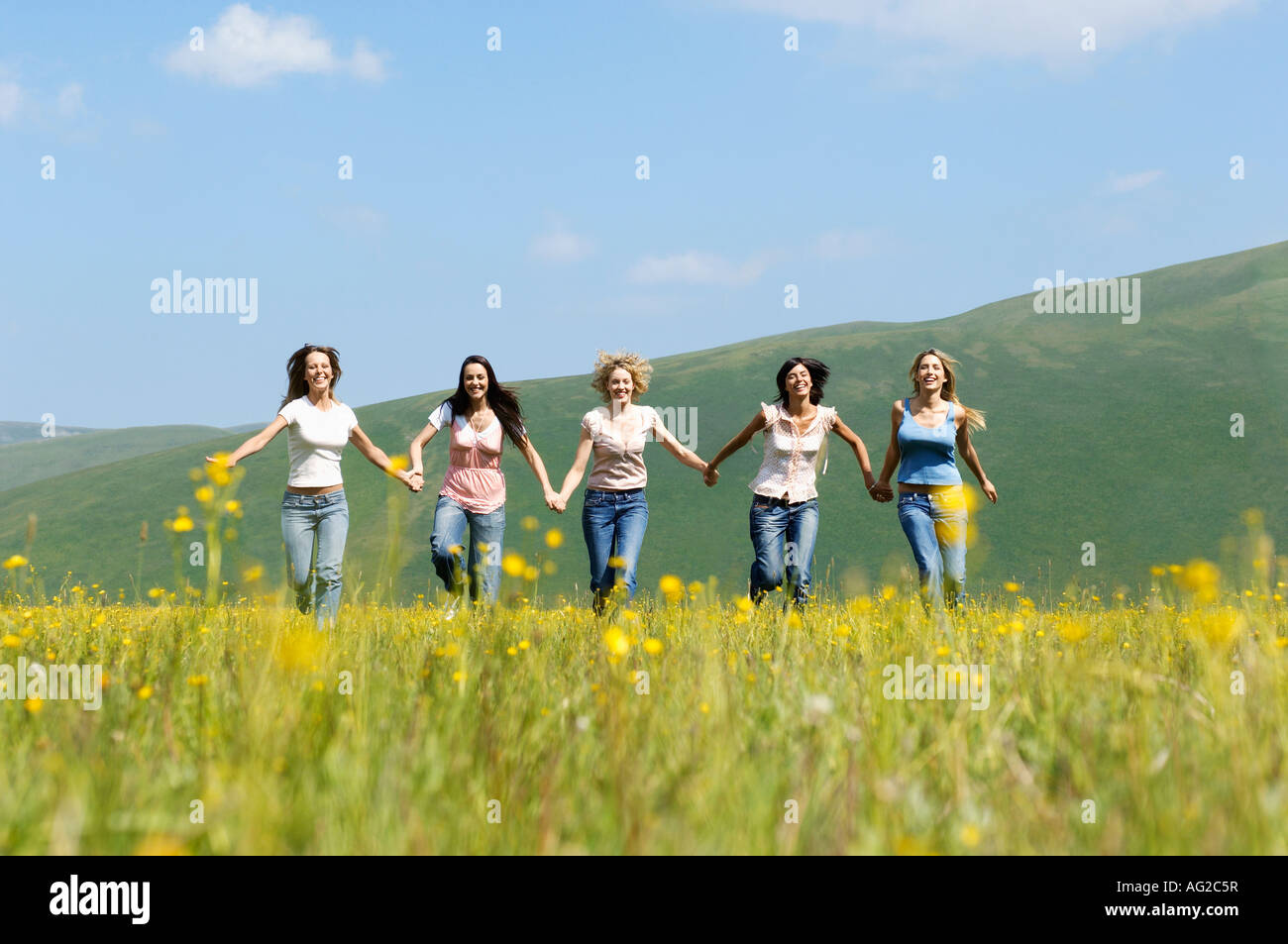 Group of friends running through mountain field, front view Stock Photo ...